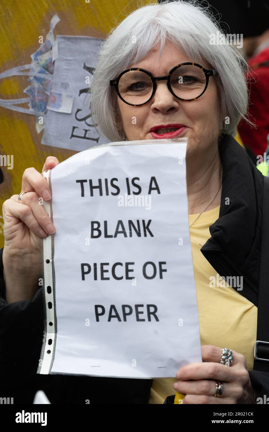 London, UK. 6 May, 2023. A protester holds a piece of paper saying ...