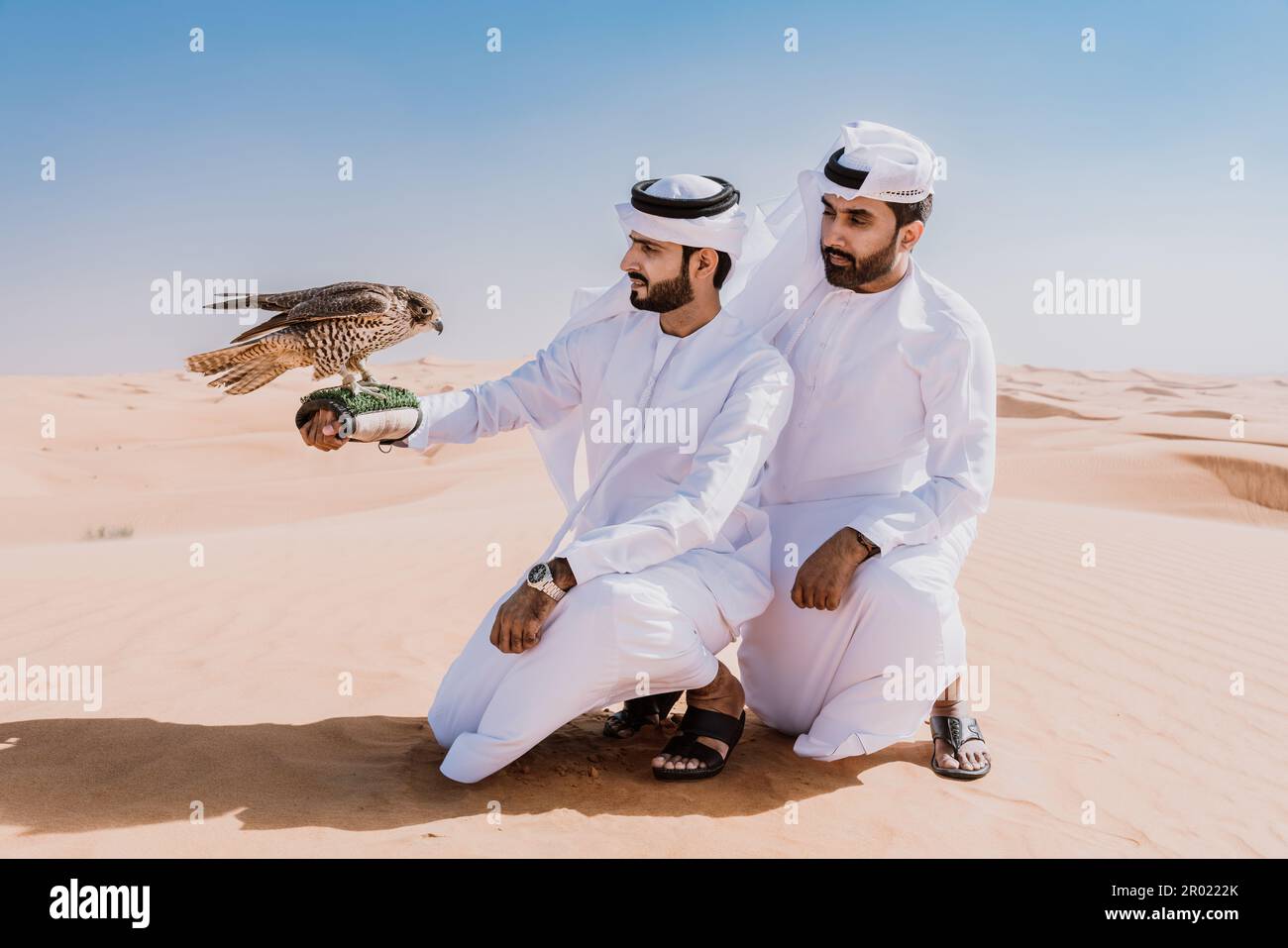 Two middle-eastern men wearing traditional emirati arab kandura bonding ...