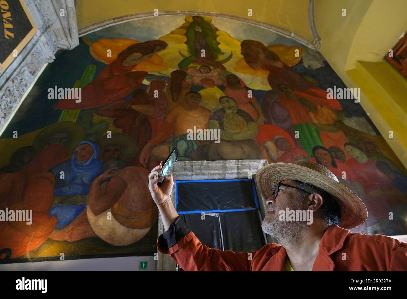 A tourist takes a photo backdropped by the "Alegoria de la Virgen de ...