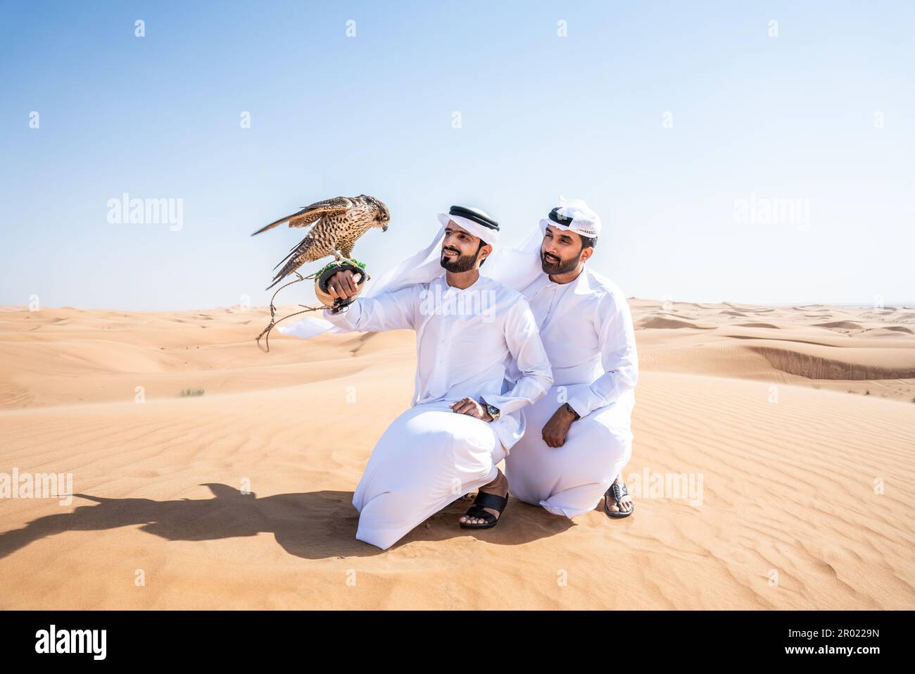 Two middle-eastern men wearing traditional emirati arab kandura bonding ...