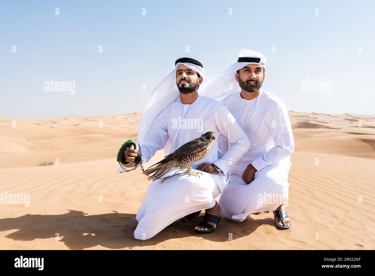 Two middle-eastern men wearing traditional emirati arab kandura bonding ...
