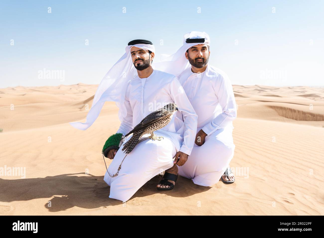 Two middle-eastern men wearing traditional emirati arab kandura bonding ...