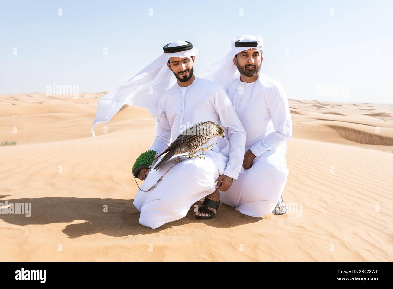 Two middle-eastern men wearing traditional emirati arab kandura bonding ...