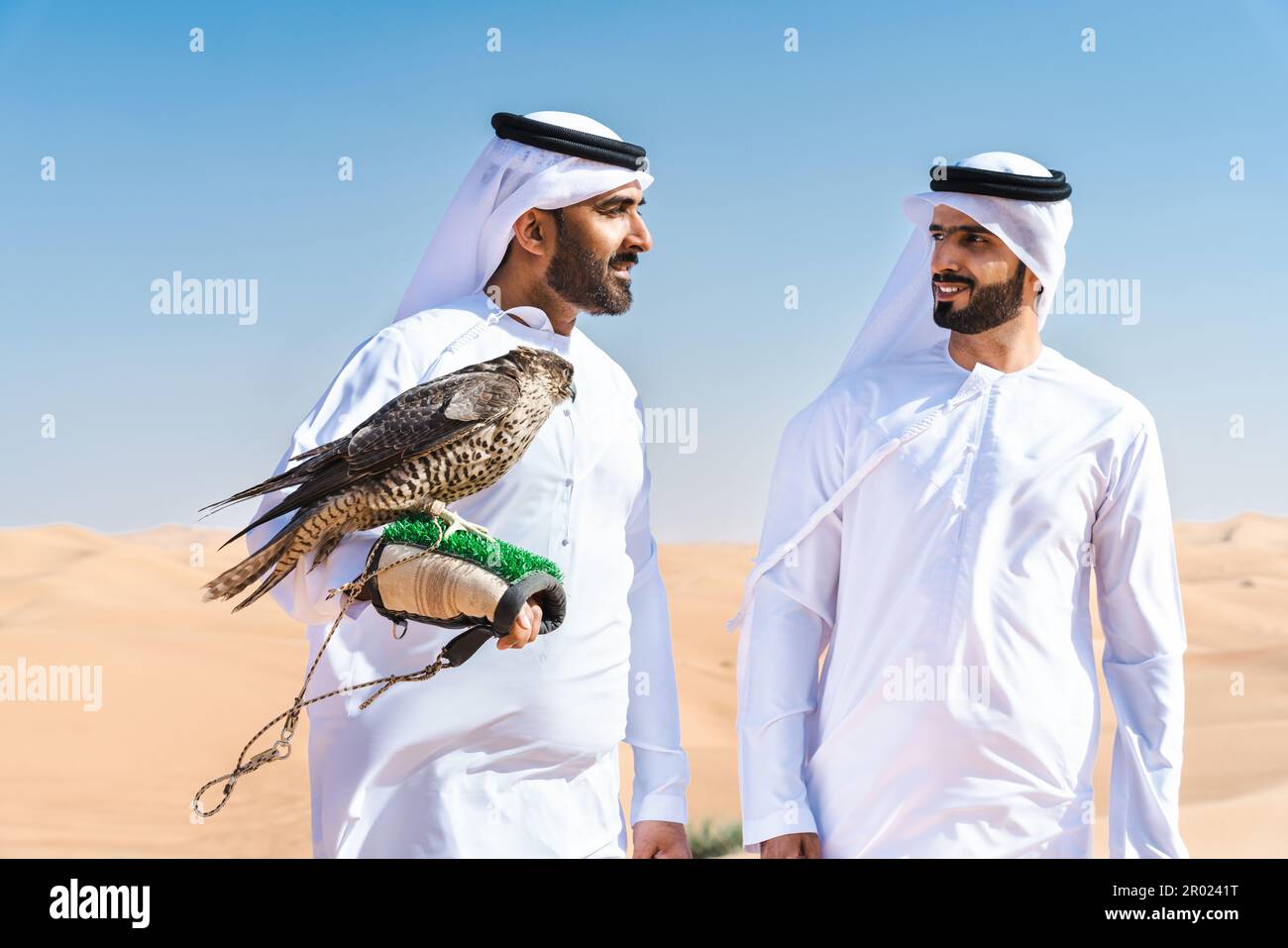 Two middle-eastern men wearing traditional emirati arab kandura bonding ...