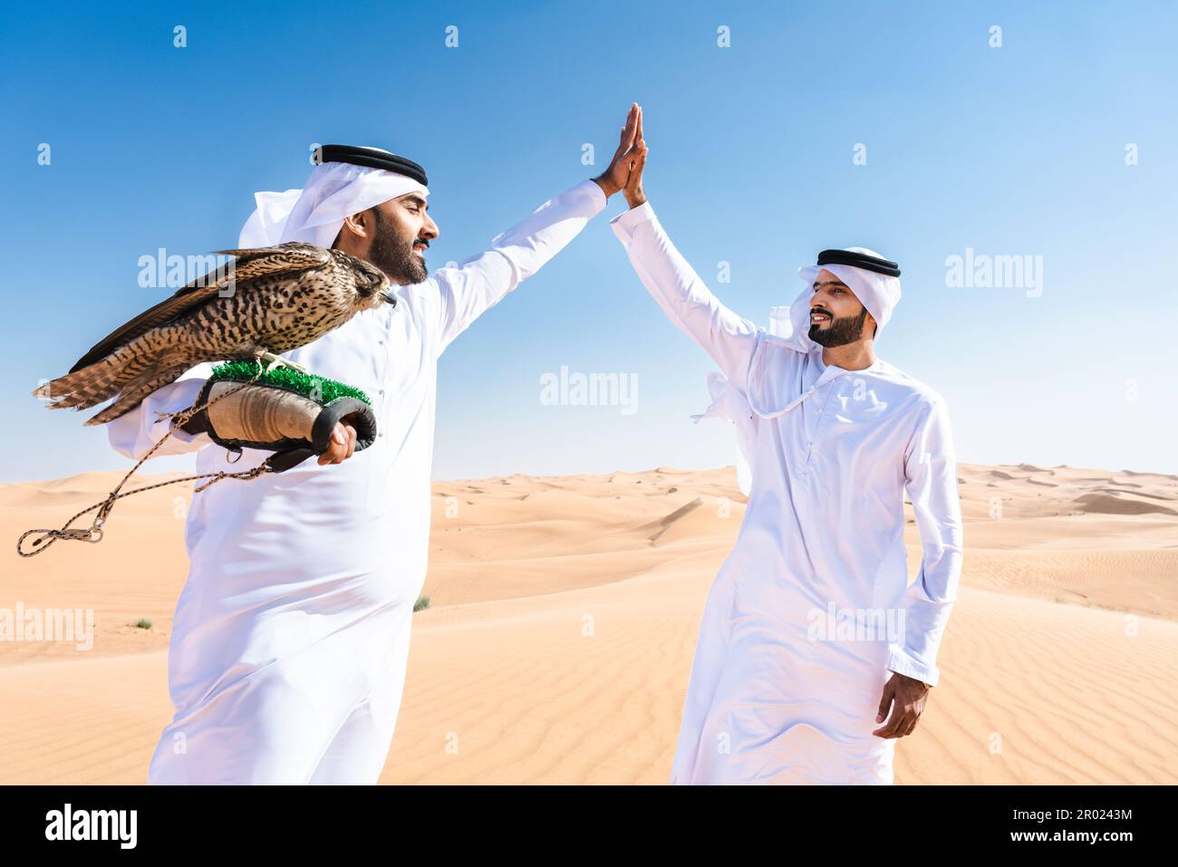 Two middle-eastern men wearing traditional emirati arab kandura bonding ...
