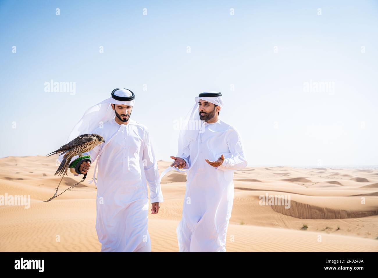 Two middle-eastern men wearing traditional emirati arab kandura bonding ...