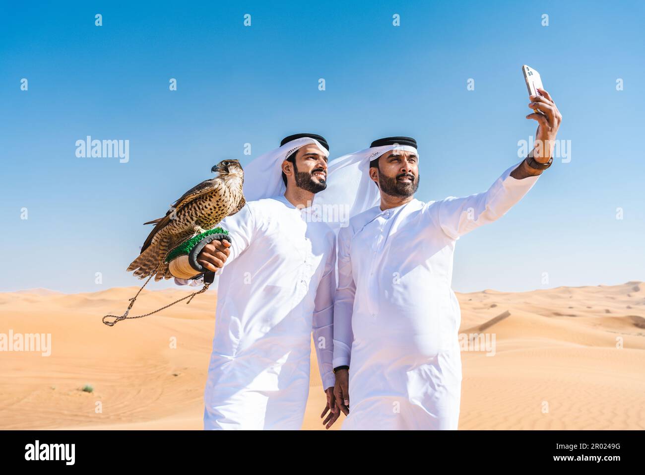 Two middle-eastern men wearing traditional emirati arab kandura bonding ...