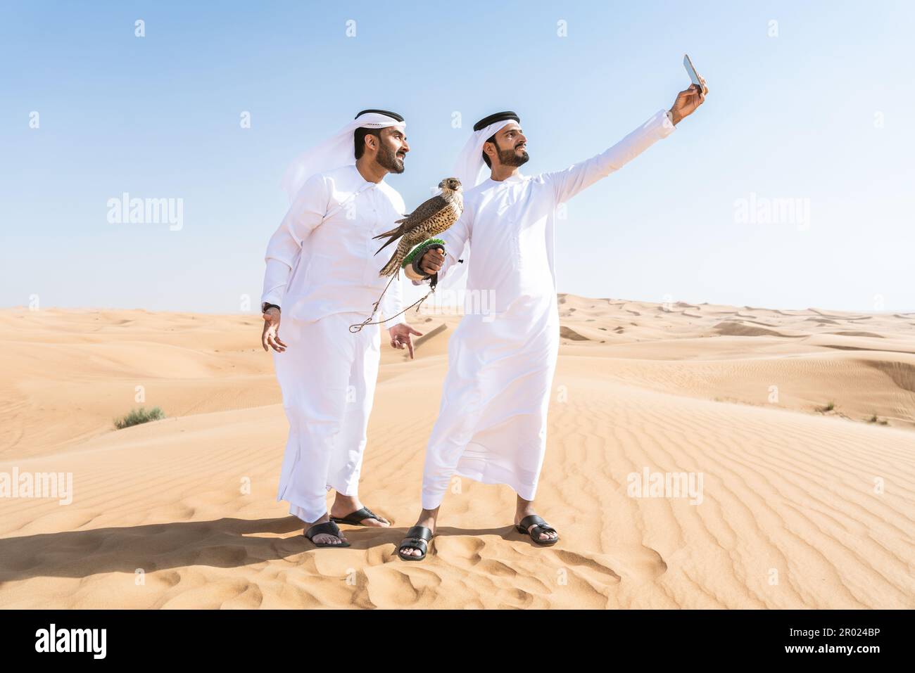 Two middle-eastern men wearing traditional emirati arab kandura bonding ...