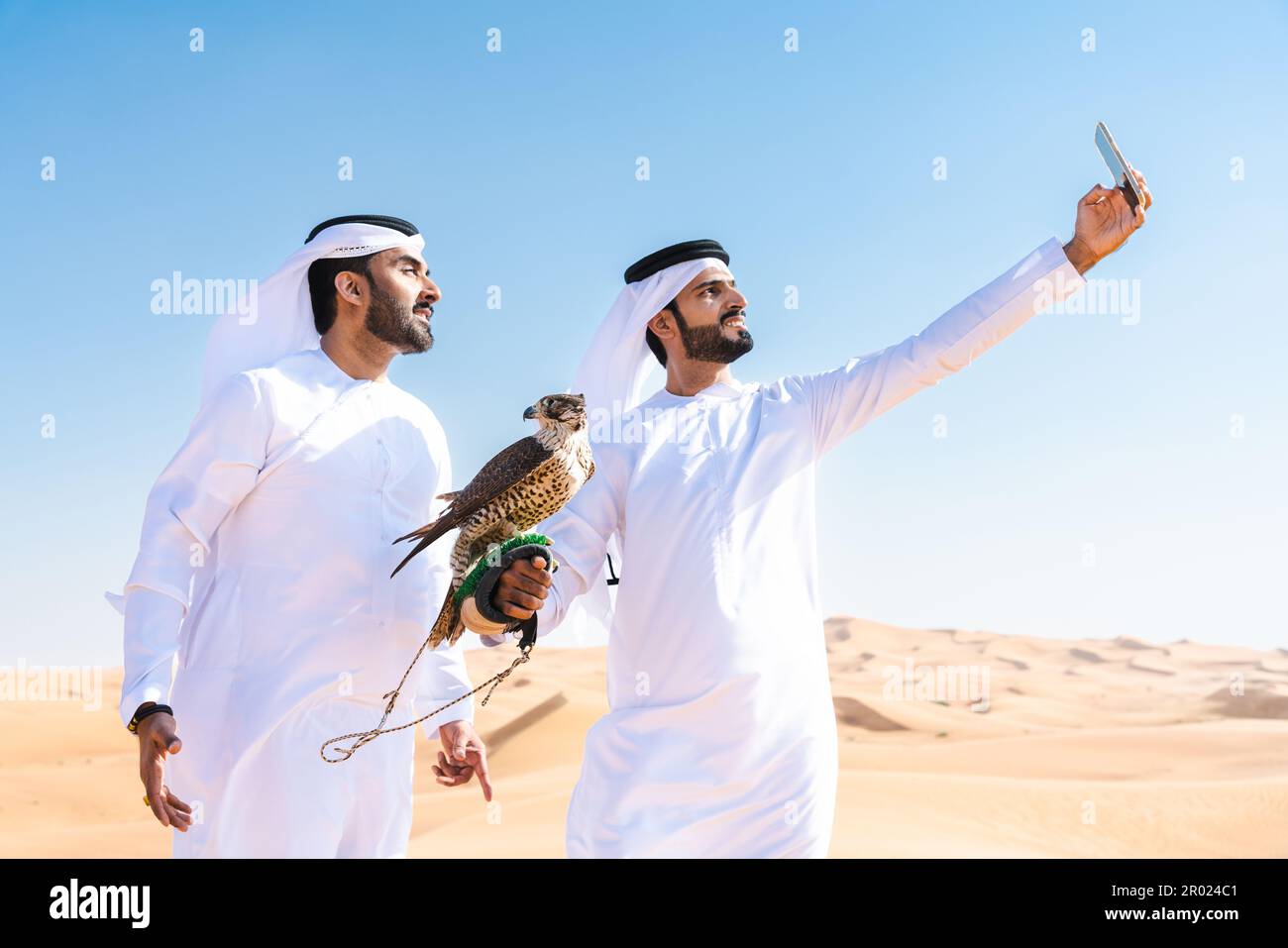 Two middle-eastern men wearing traditional emirati arab kandura bonding ...
