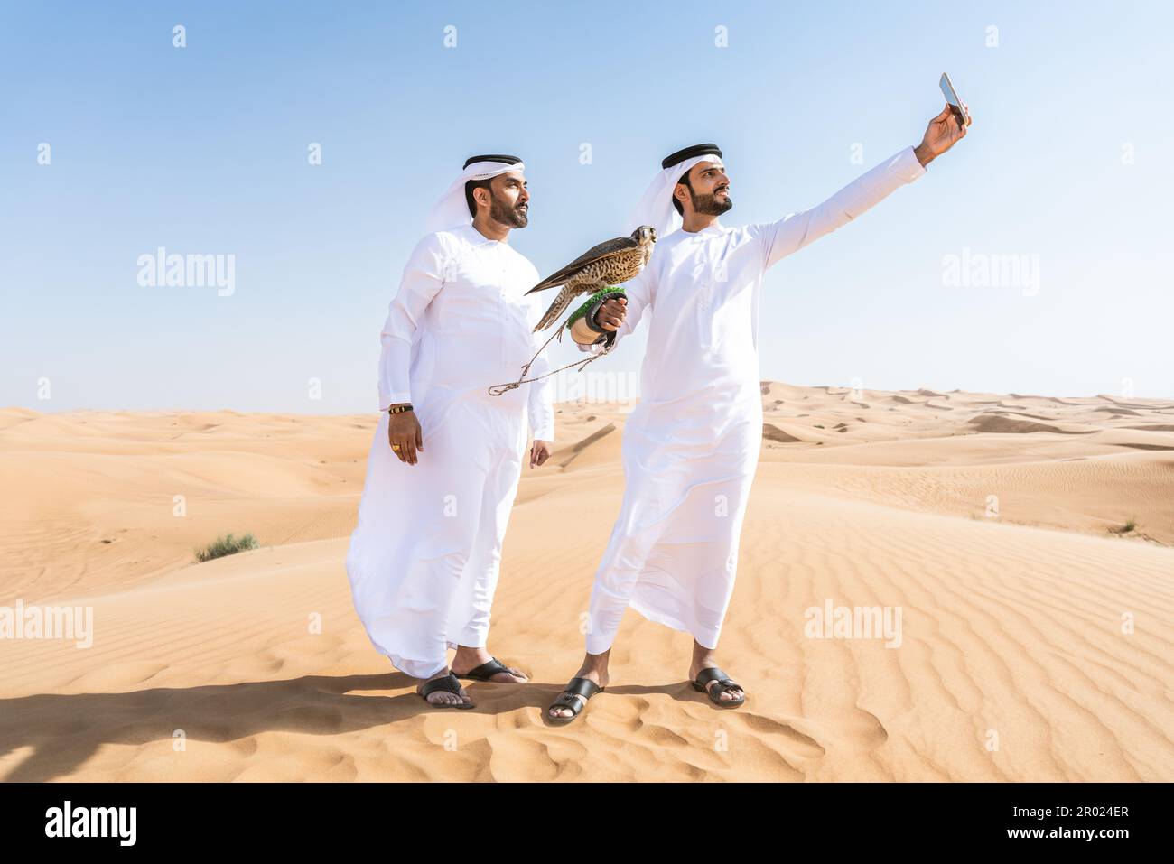 Two middle-eastern men wearing traditional emirati arab kandura bonding ...
