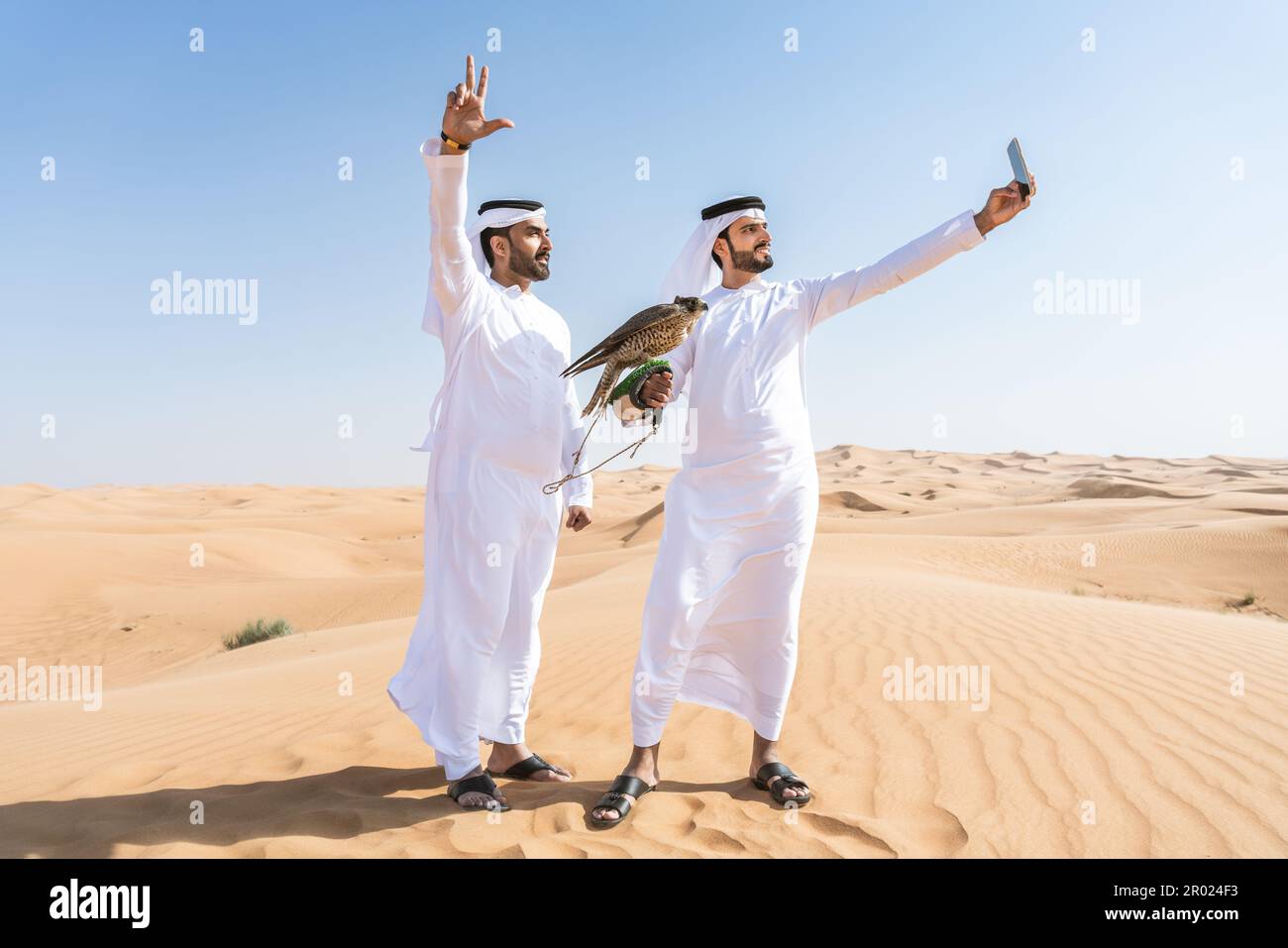 Two middle-eastern men wearing traditional emirati arab kandura bonding ...