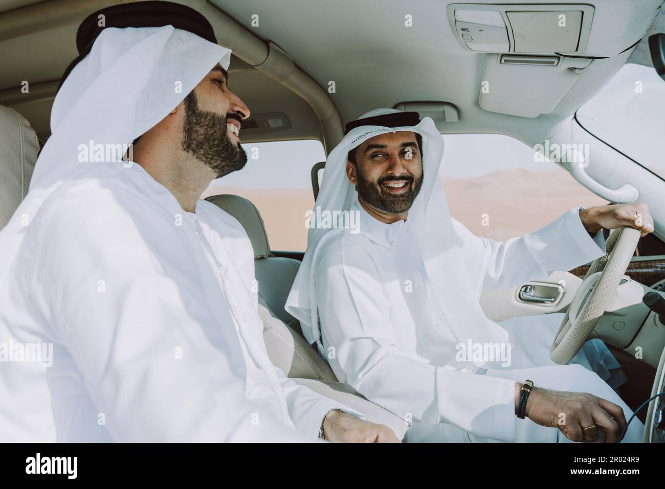 Two middle-eastern men wearing traditional emirati arab kandura driving ...