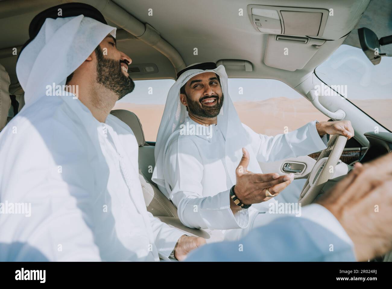 Two middle-eastern men wearing traditional emirati arab kandura driving ...
