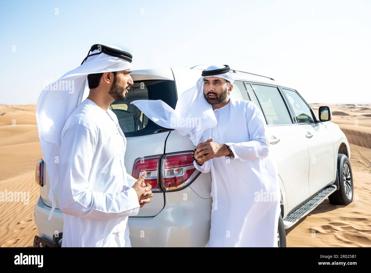 Two middle-eastern men wearing traditional emirati arab kandura driving ...