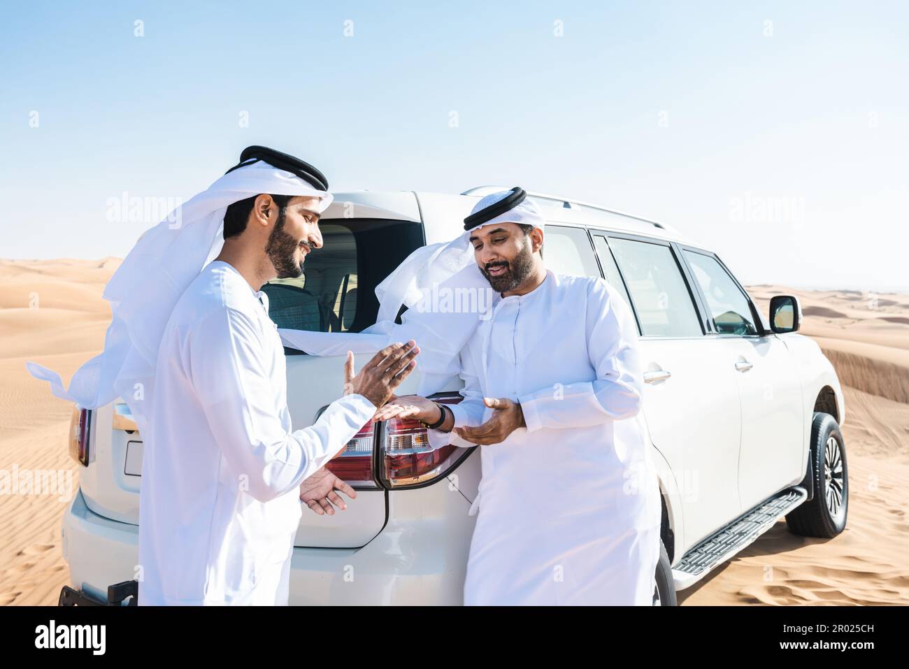 Two middle-eastern men wearing traditional emirati arab kandura driving ...