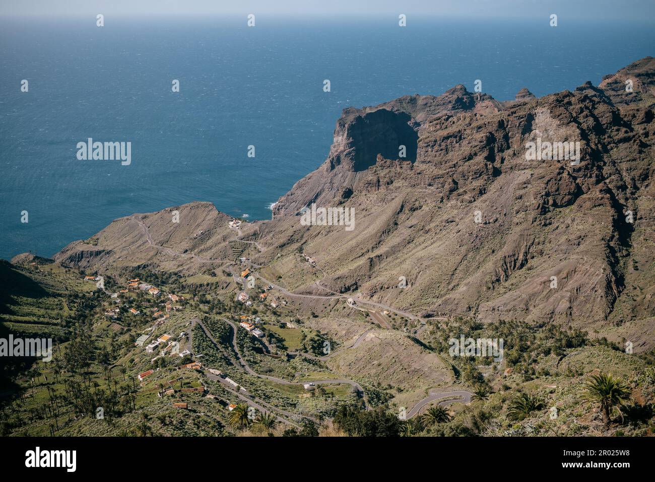 An aerial view of a winding coastal road leading to the horizon, lined ...