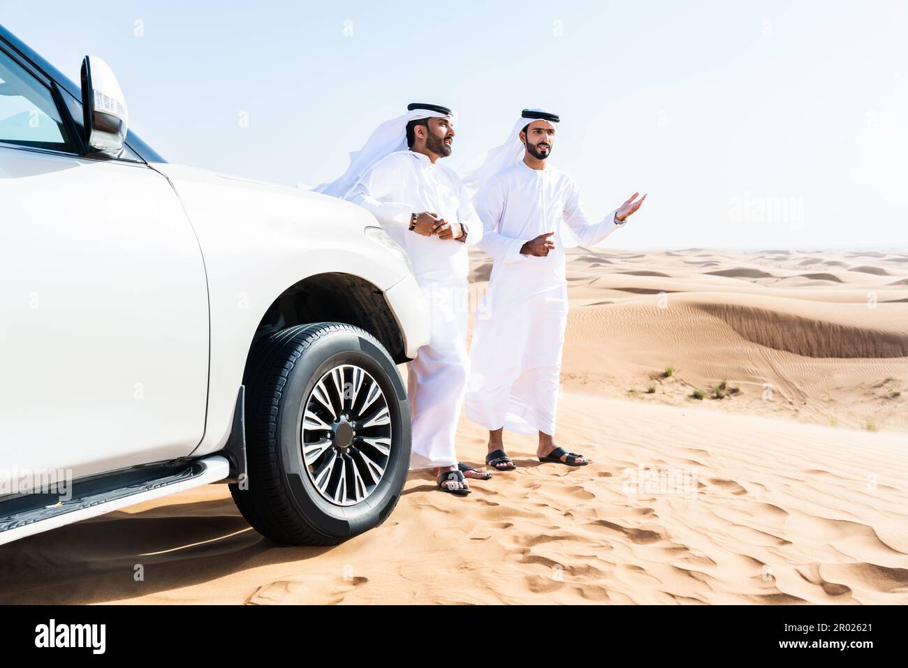 Two middle-eastern men wearing traditional emirati arab kandura driving ...
