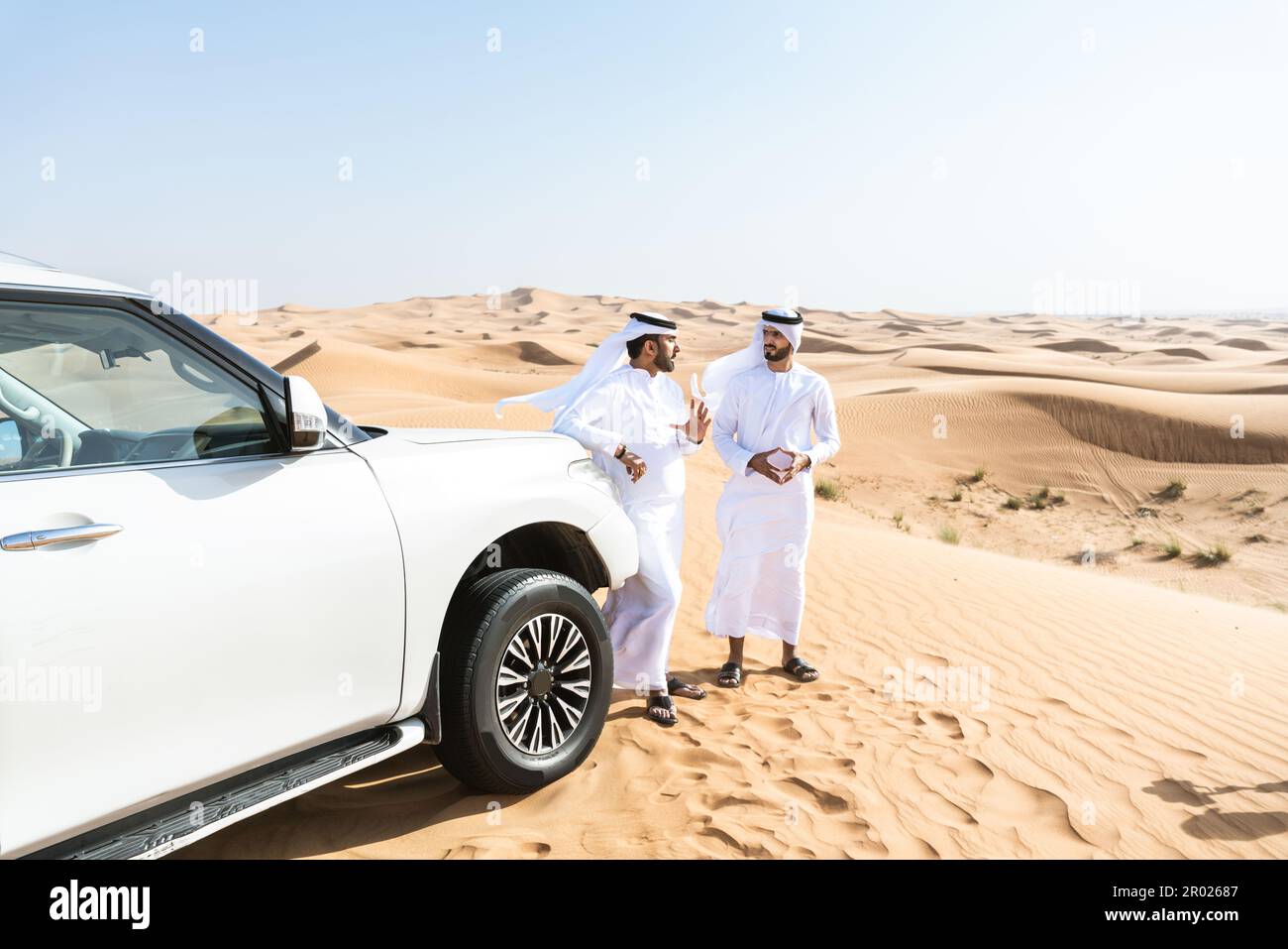 Two middle-eastern men wearing traditional emirati arab kandura driving ...