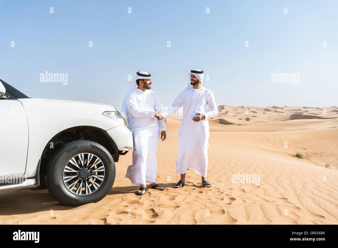Two middle-eastern men wearing traditional emirati arab kandura driving ...