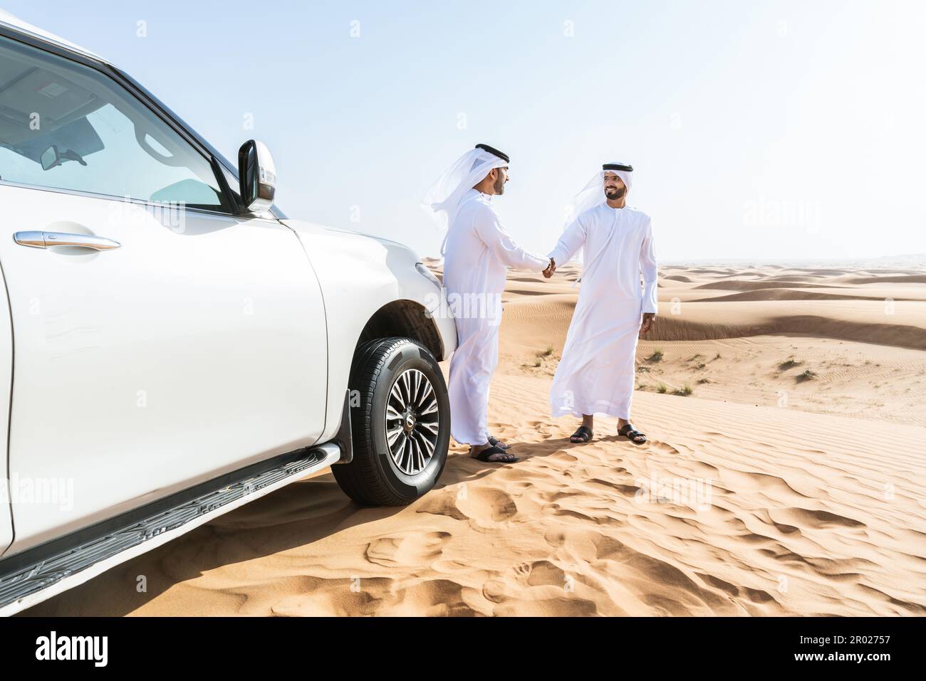 Two middle-eastern men wearing traditional emirati arab kandura driving ...