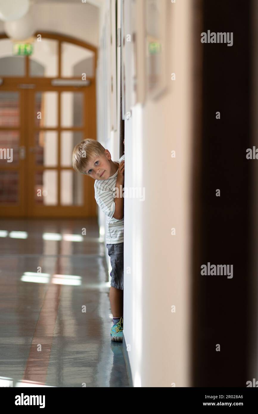 Boy playing hide and seek in corridor, Active kid looking out while ...