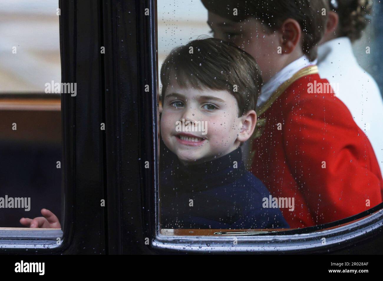 Britain's Prince Louis of Wales smiles through the window as he travels ...