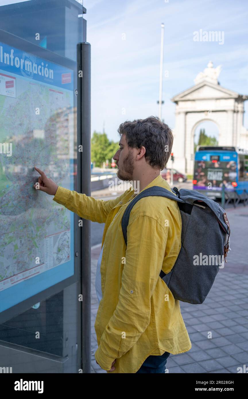 Handsome male traveler with backpack checking location and destination ...