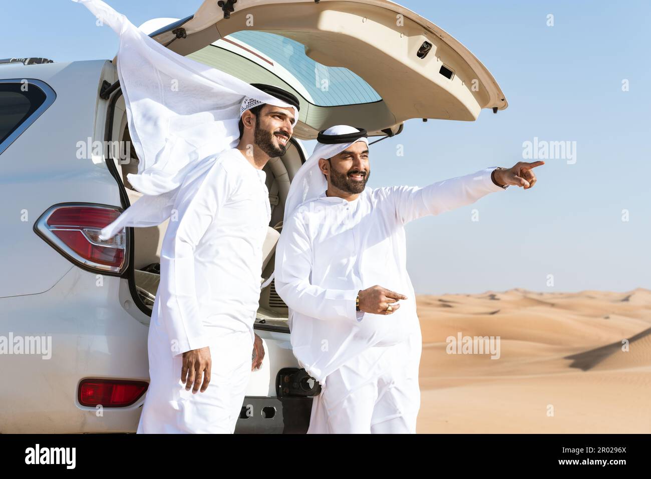 Two middle-eastern men wearing traditional emirati arab kandura driving ...