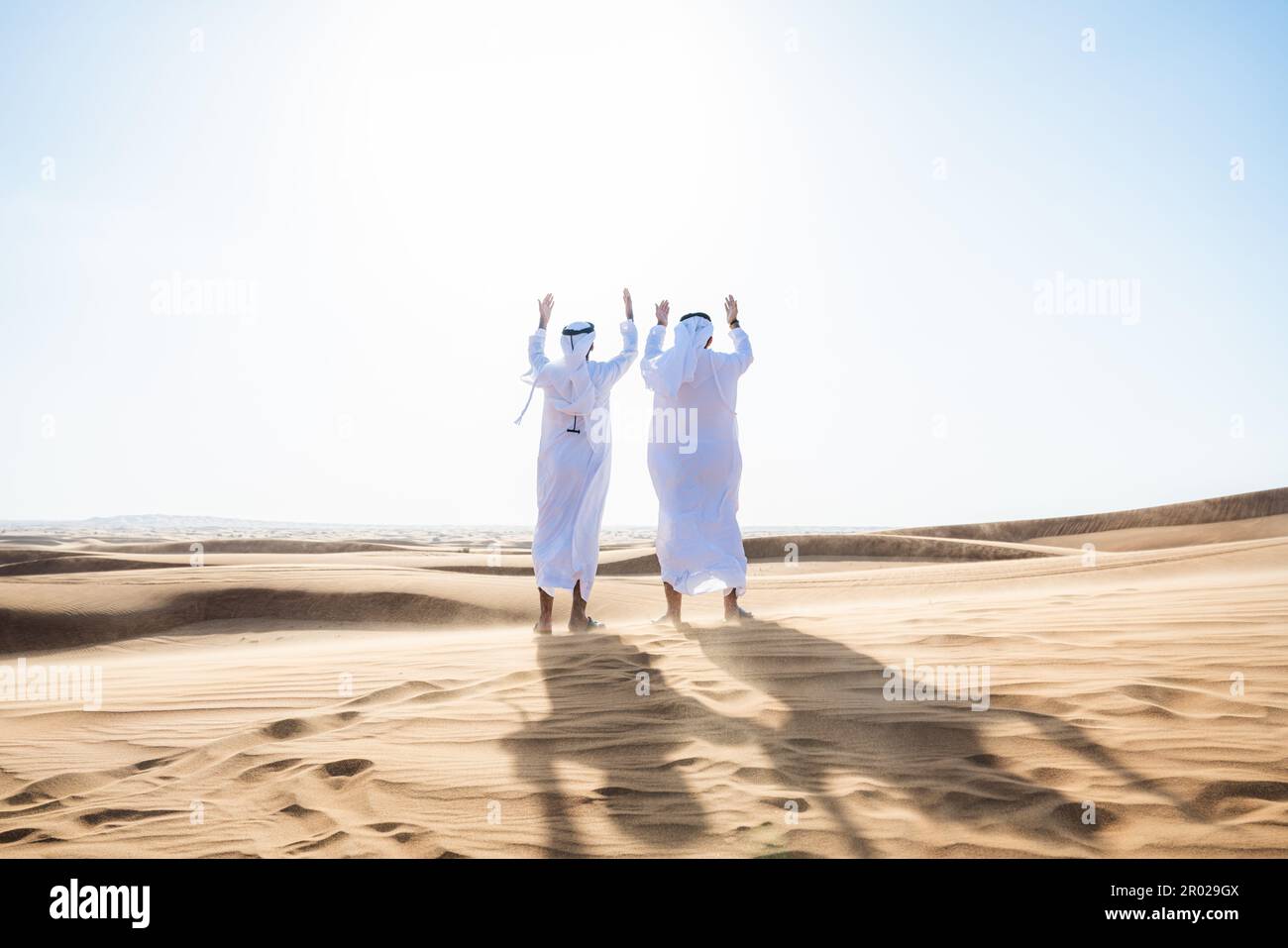 Two middle-eastern men wearing traditional emirati arab kandura bonding ...