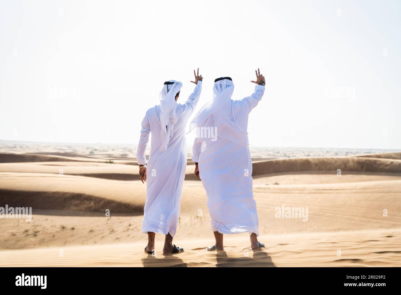 Two middle-eastern men wearing traditional emirati arab kandura bonding ...