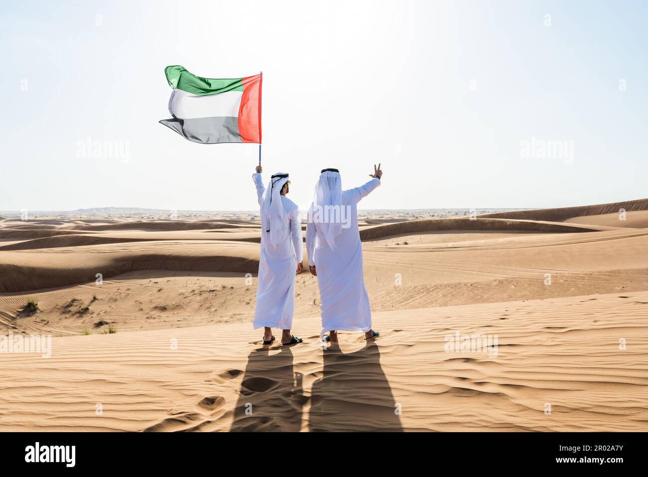 Two middle-eastern men wearing traditional emirati arab kandura bonding ...