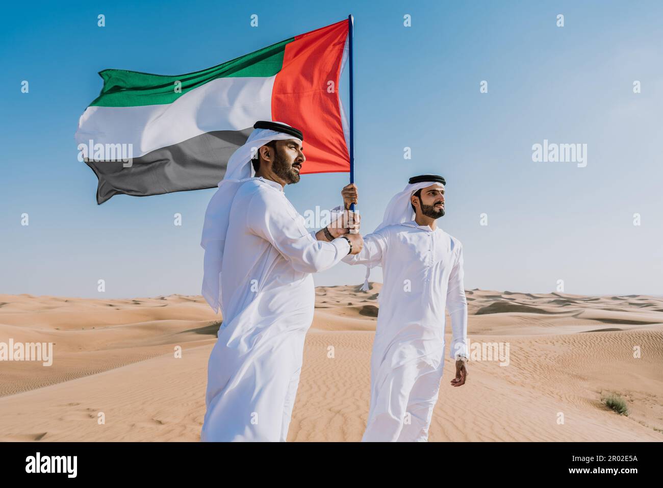 Two middle-eastern men wearing traditional emirati arab kandura bonding ...