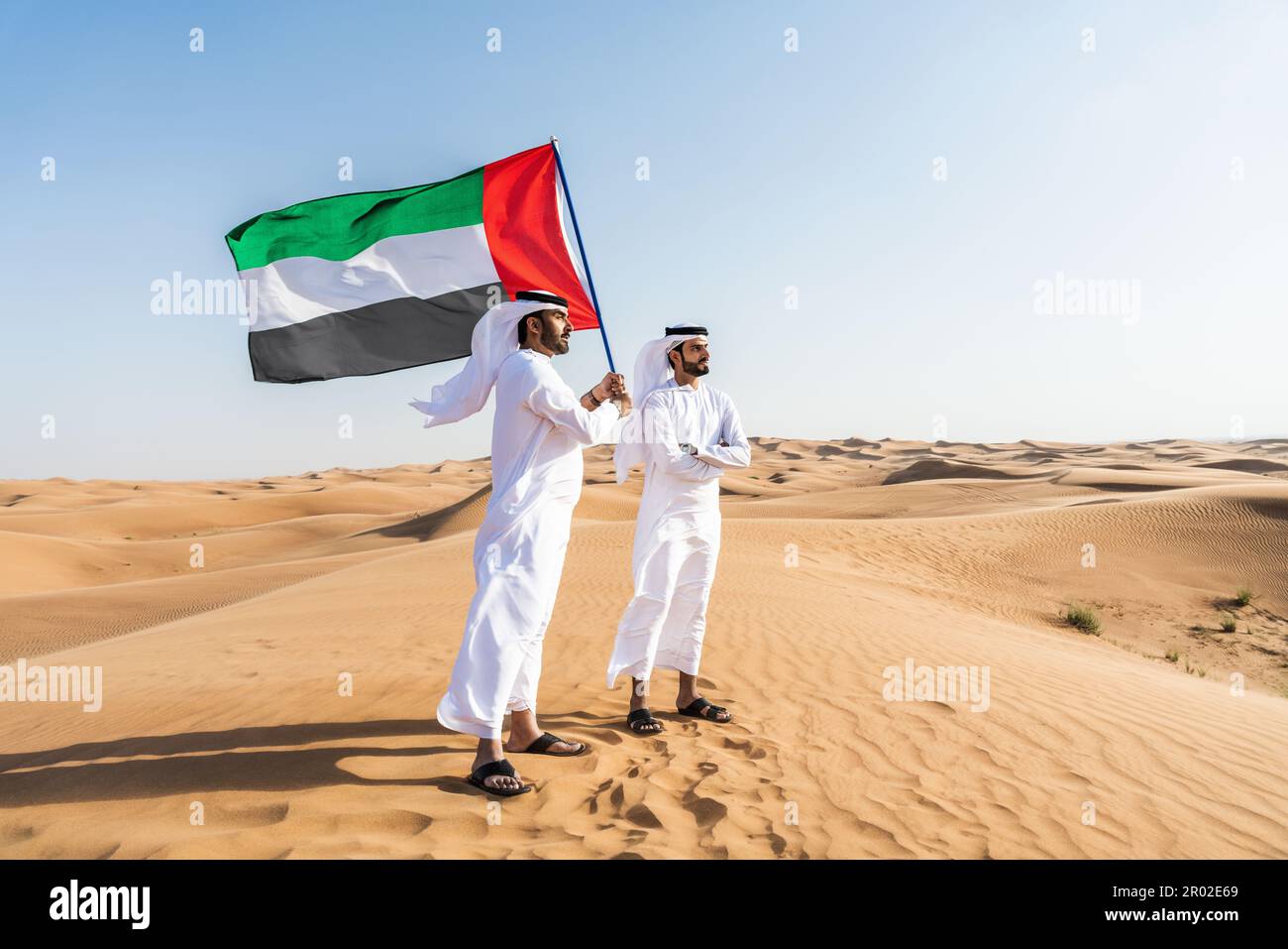 Two middle-eastern men wearing traditional emirati arab kandura bonding ...
