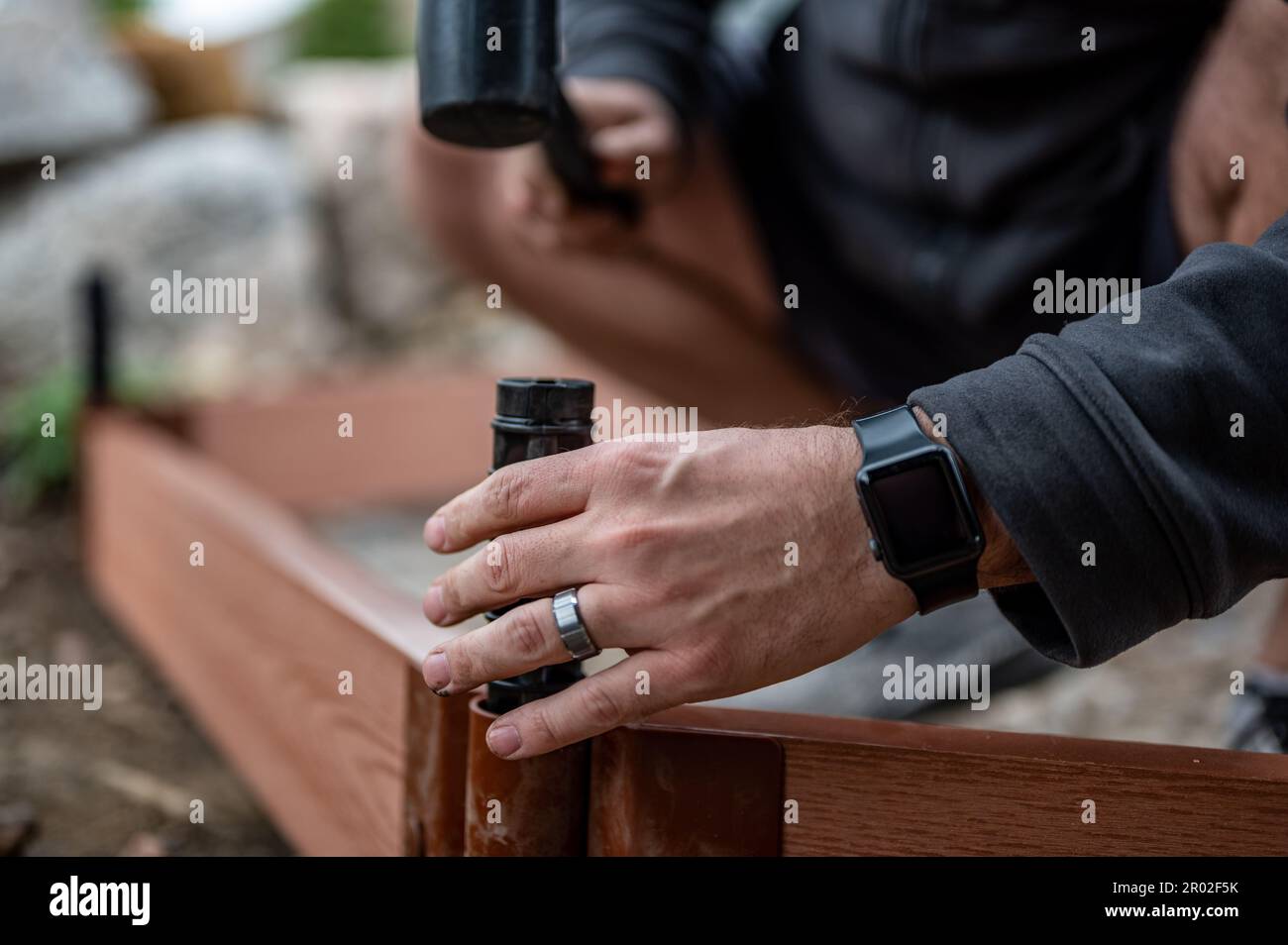 Actively driving a border stake with a rubber mallet to assemble a ...