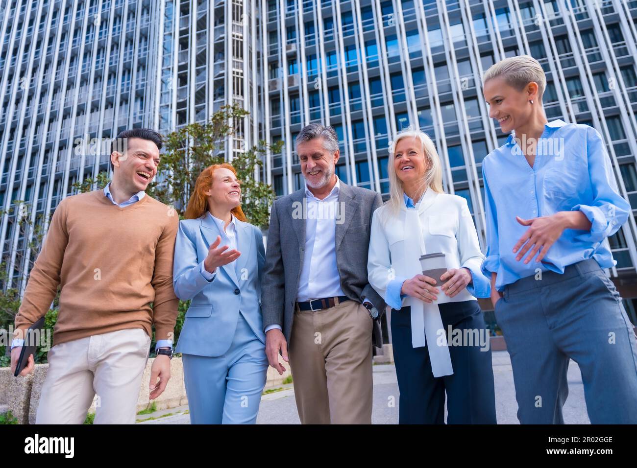 Group of coworkers walking going to work outdoors in a corporate office ...