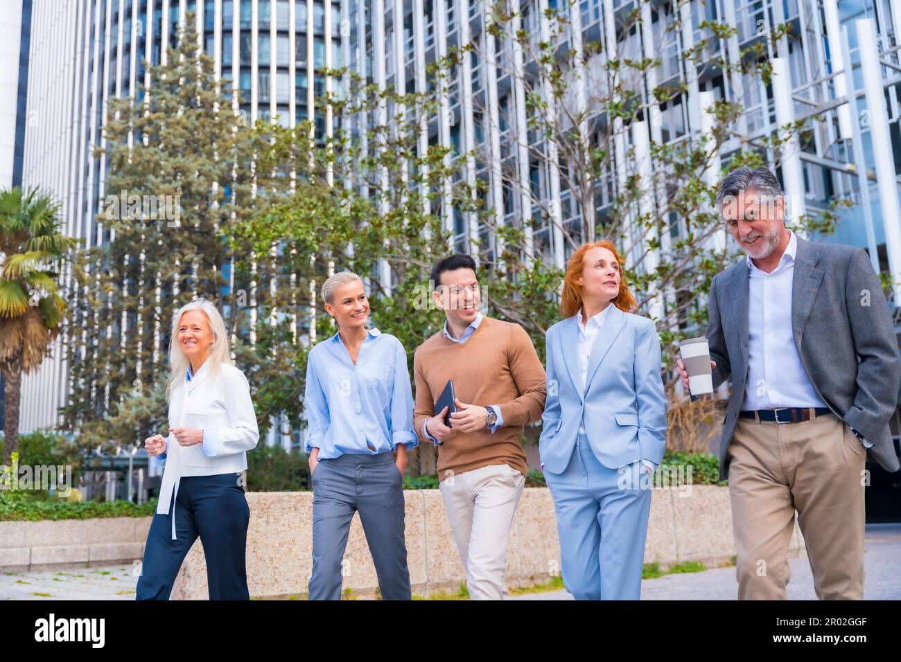 Group of coworkers walking going to work outdoors in a corporate office ...