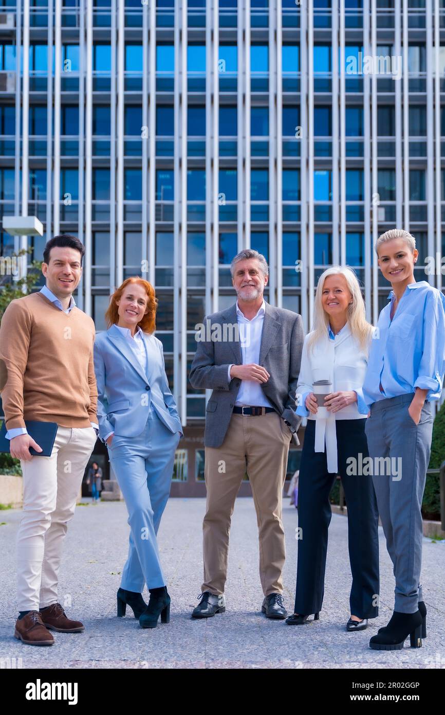 Portrait of cheerful group of coworkers walking outdoors in a corporate ...