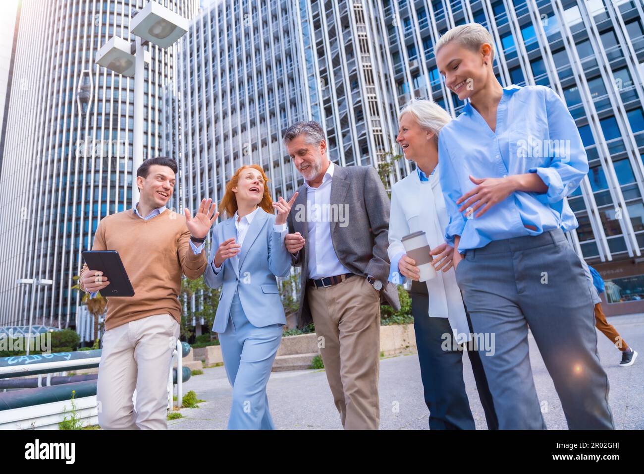 Group of coworkers walking going to work outdoors in a corporate office ...