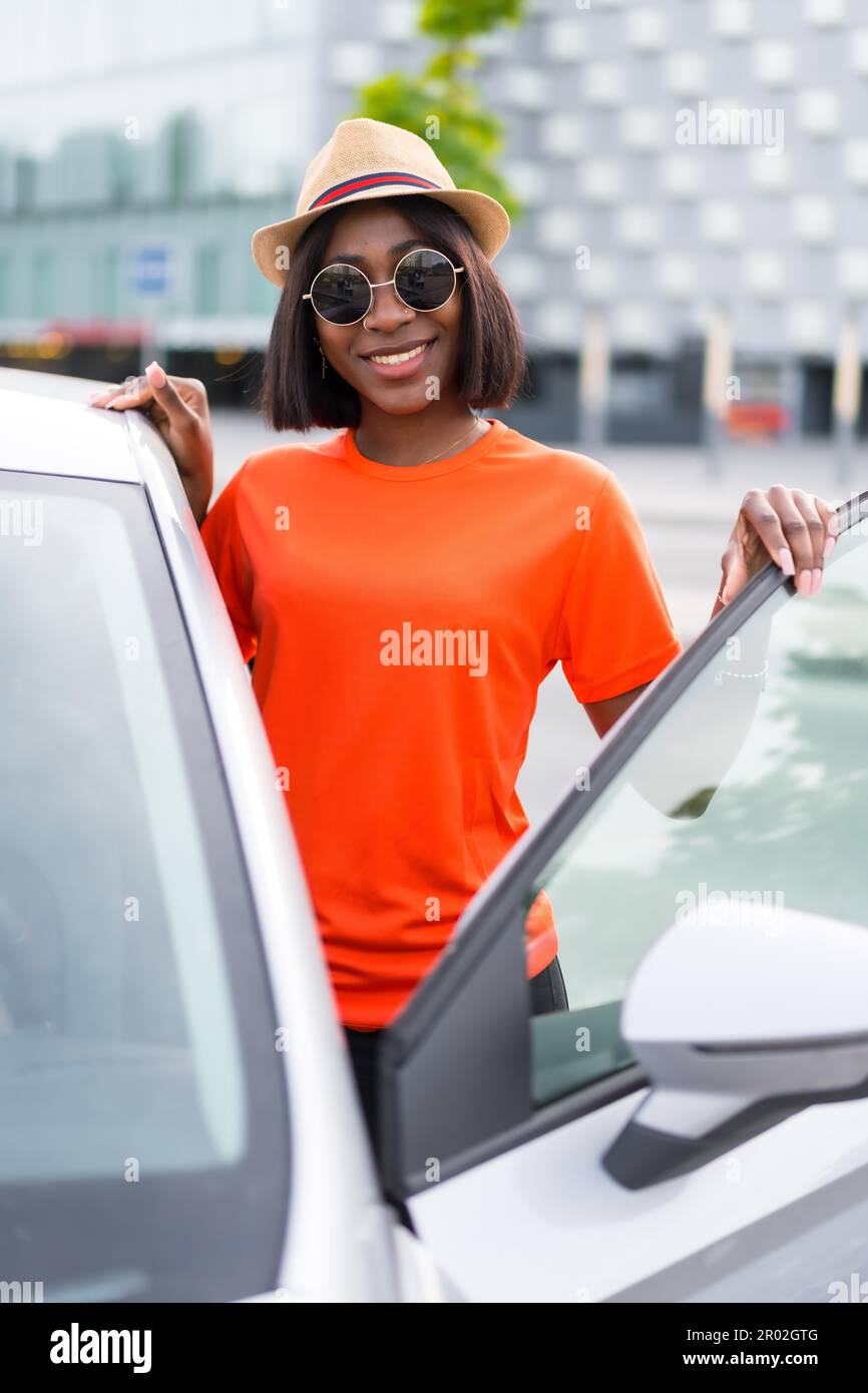 Summer vibes: young black woman in orange shirt and sunglasses getting ...
