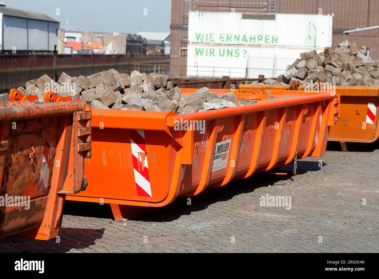 Container, orange skip for construction waste standing on the road in ...
