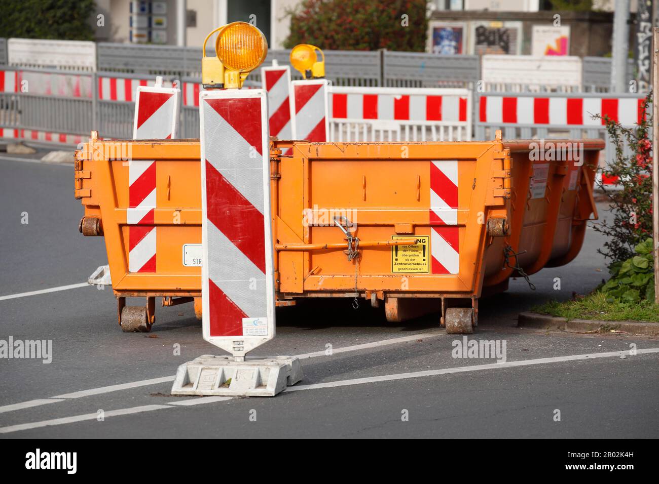 Container, orange skip for building rubble with barrier beacons ...