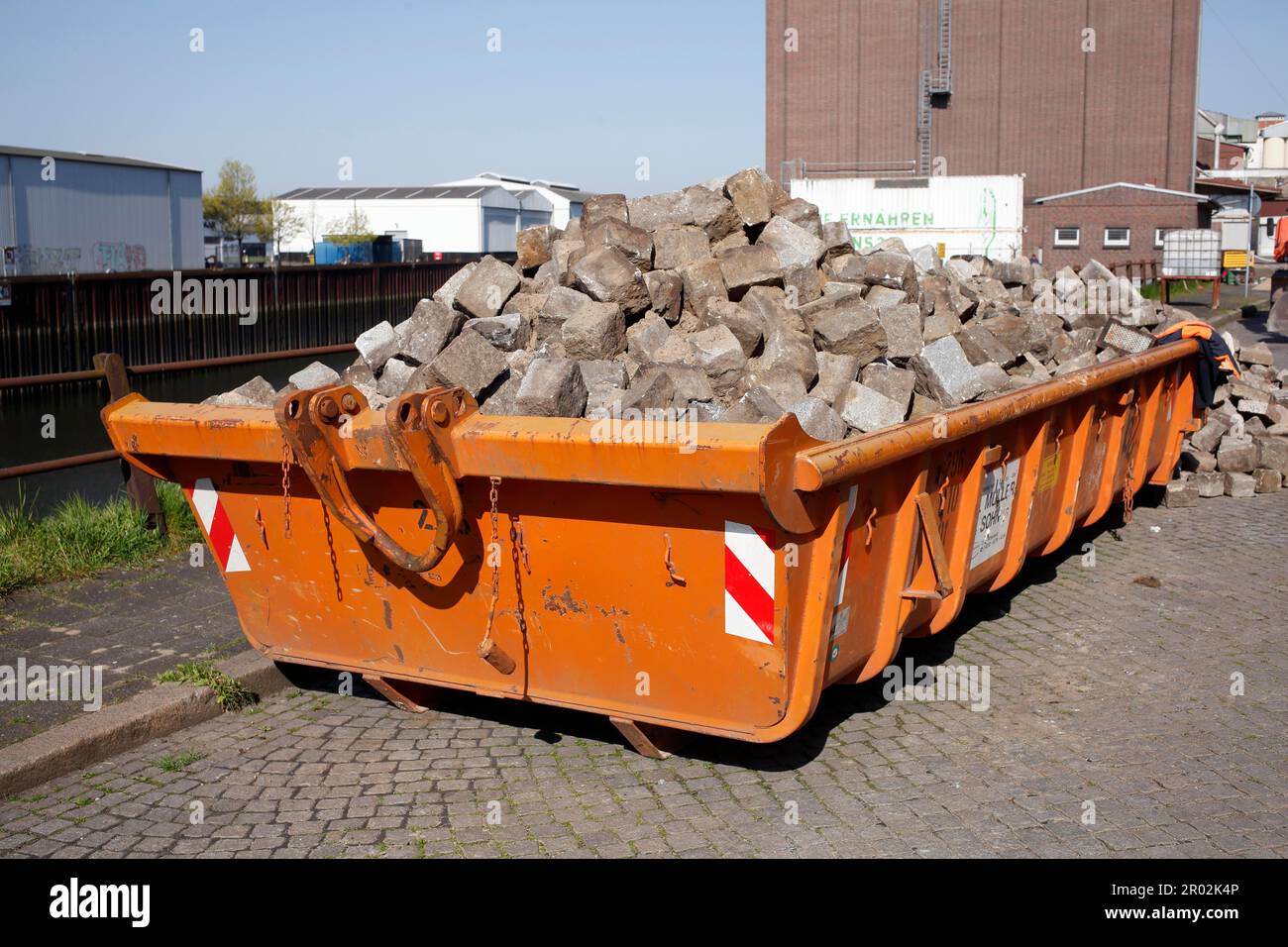 Container, orange skip for construction waste standing on the road in ...