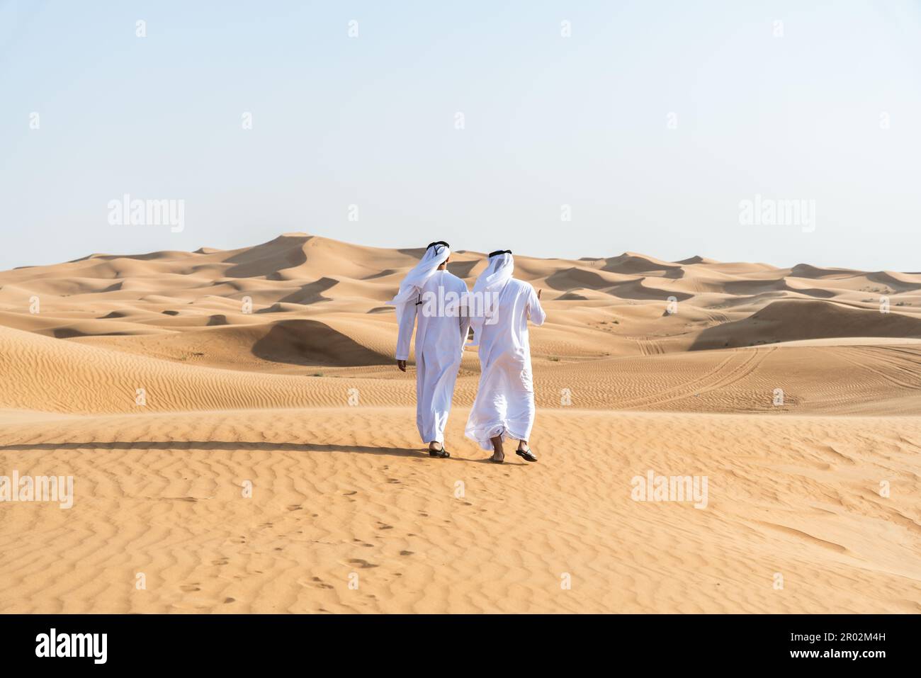 Two middle-eastern men wearing traditional emirati arab kandura bonding ...