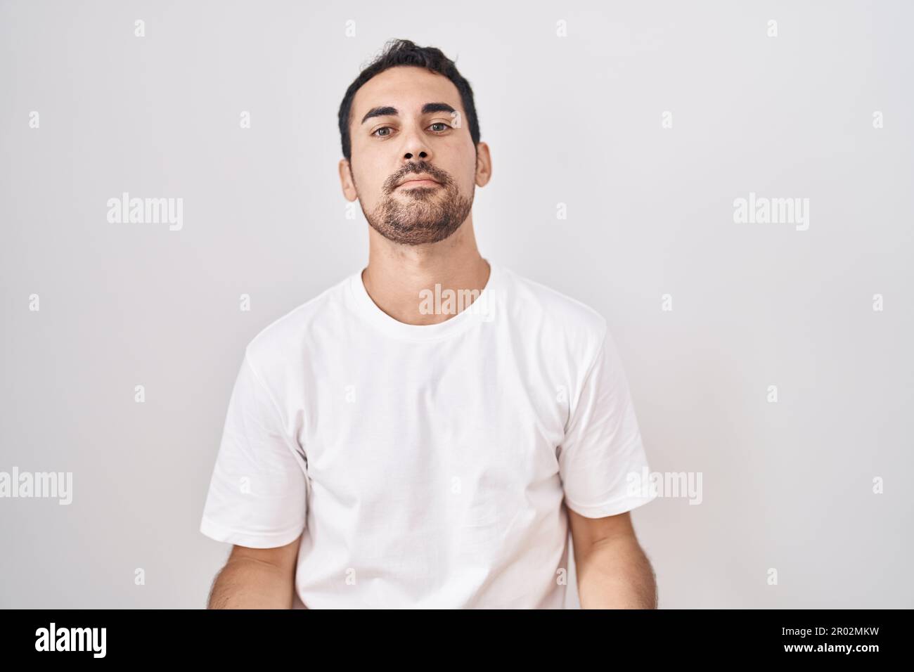 Handsome hispanic man standing over white background clueless and ...