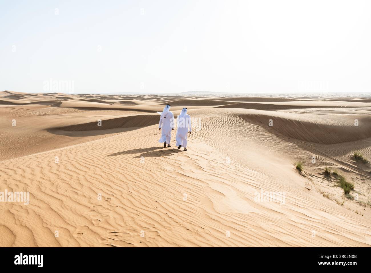 Two middle-eastern men wearing traditional emirati arab kandura bonding ...