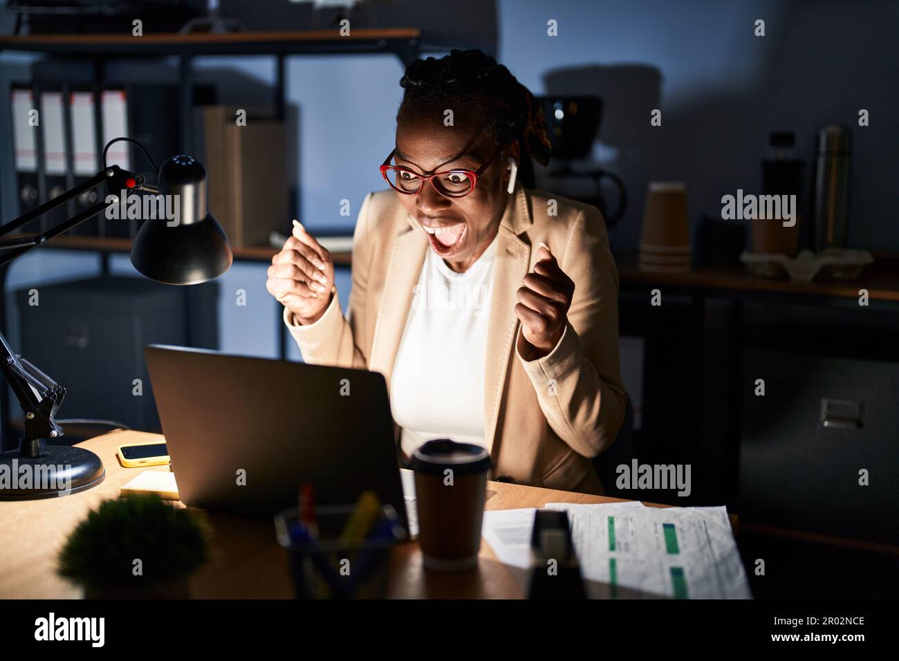 Beautiful black woman working at the office at night celebrating crazy ...