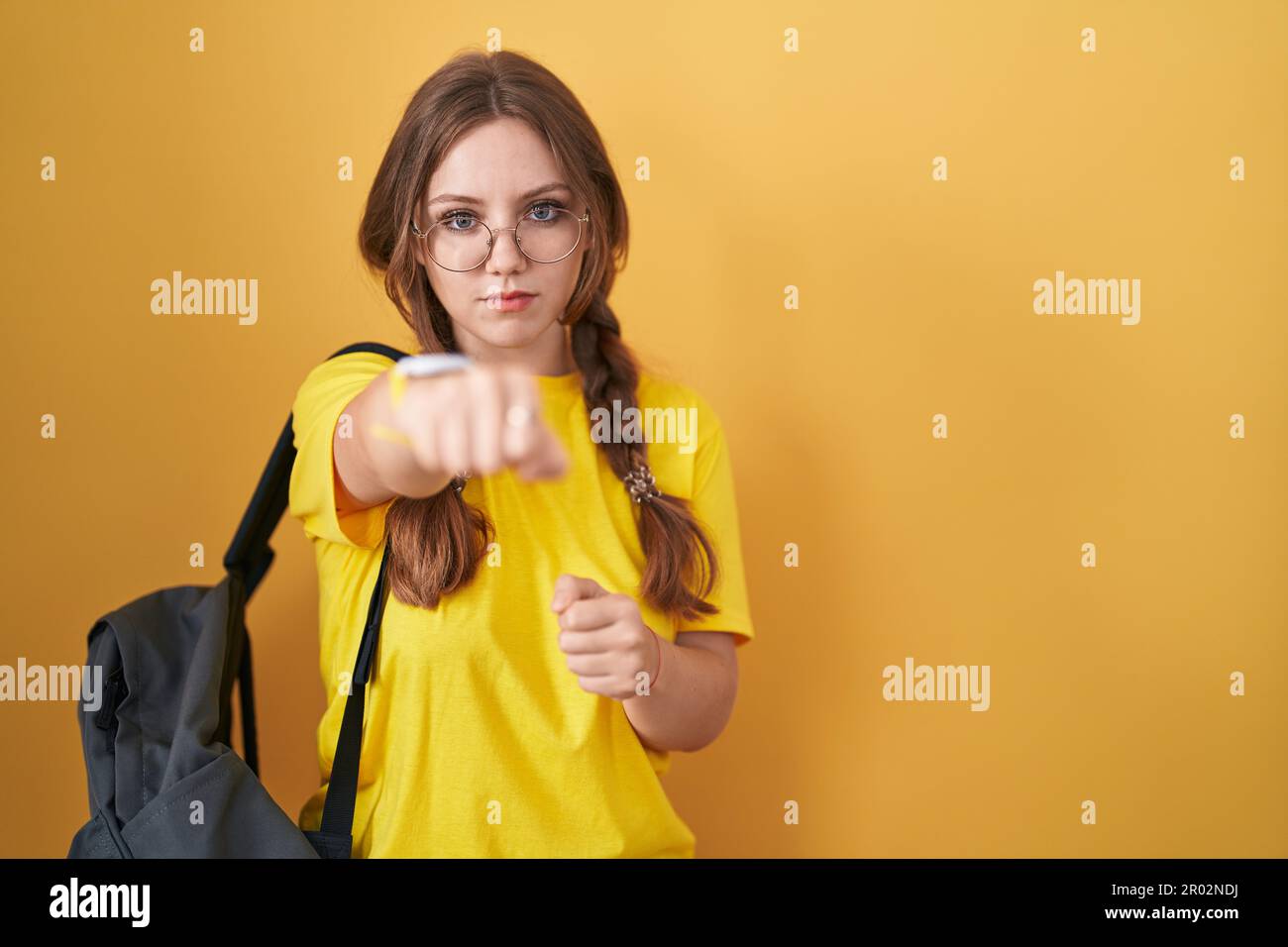 Young caucasian woman wearing student backpack over yellow background ...