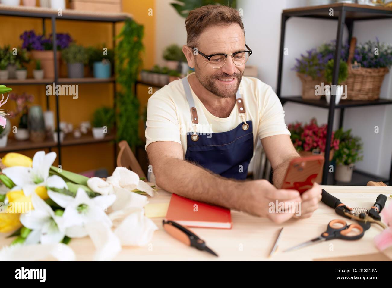 Middle age man florist smiling confident using smartphone at flower ...