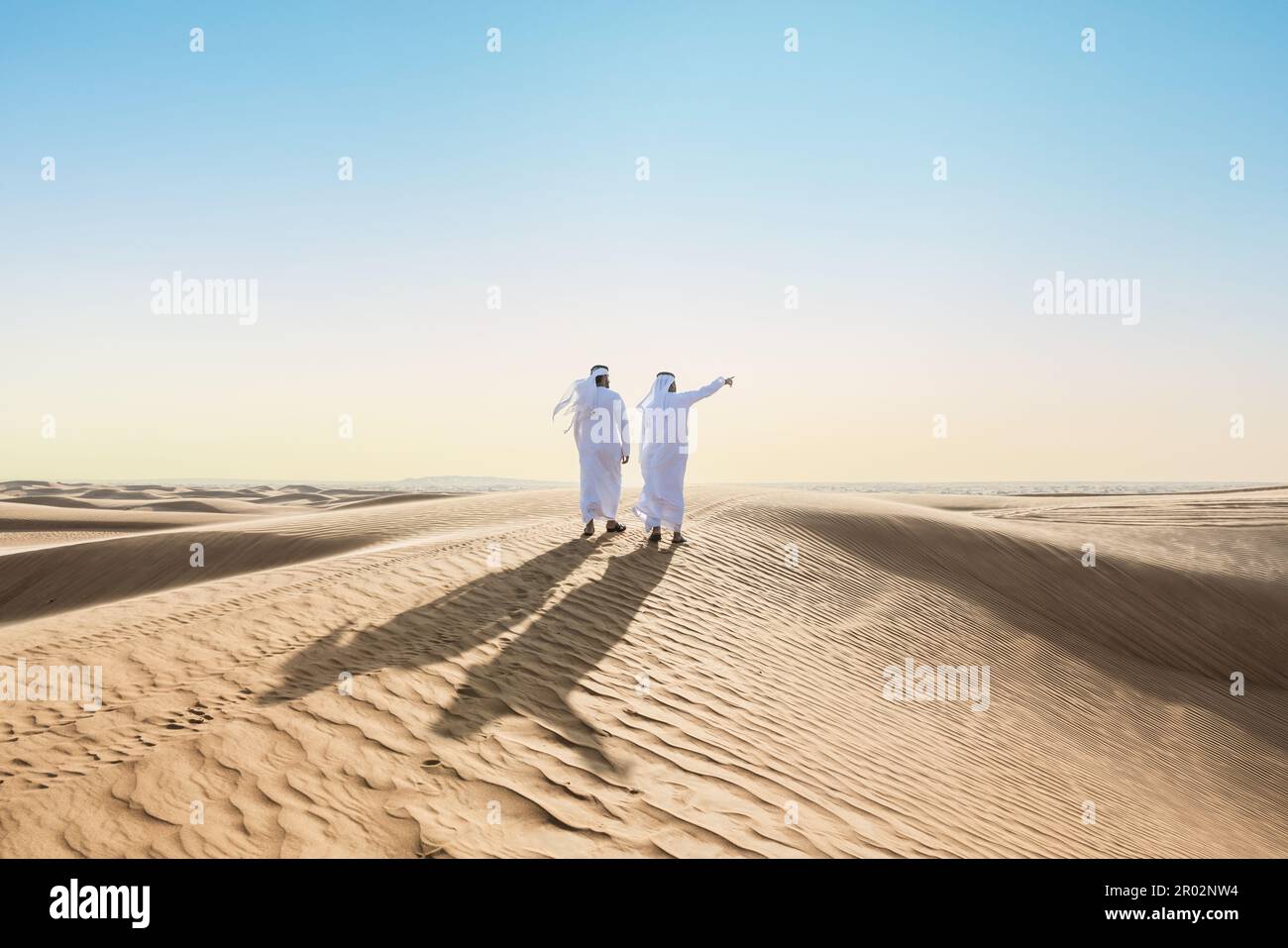 Two middle-eastern men wearing traditional emirati arab kandura bonding ...