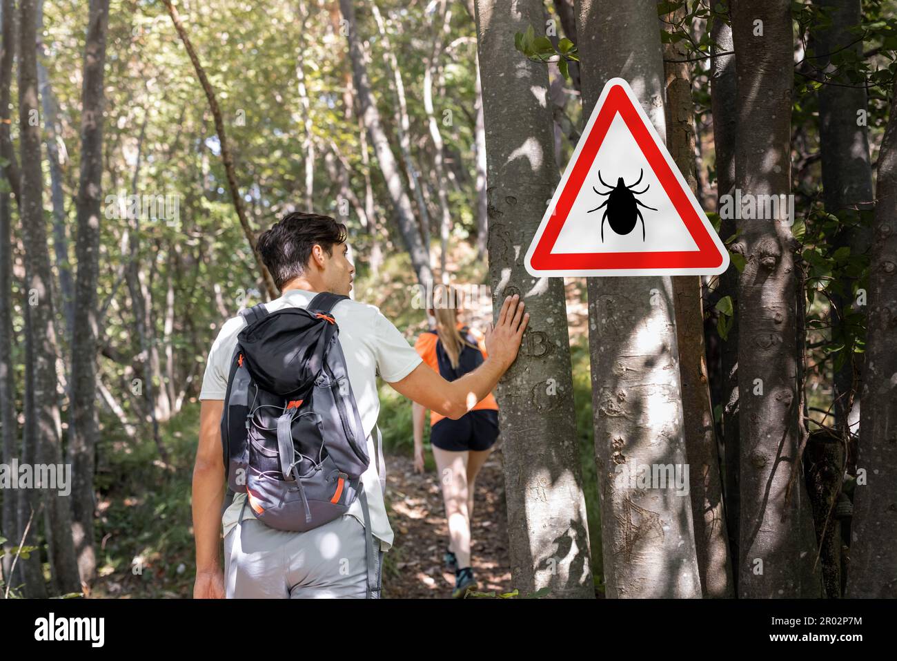 Man and woman hiking in Infected ticks forest with warning sign. Risk ...